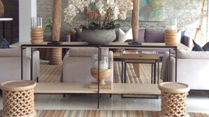 Uma sala de estar moderna com uma parede de pedra, uma grande planta de orquídea e um quadro.