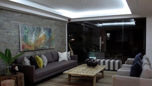Uma sala de estar moderna com um sofá cinzento, tapete riscado e uma grande pintura abstrata na parede.