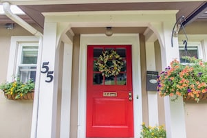 Uma porta vermelha com uma guirlanda, o número 5 e cestos de flores em ambos os lados.