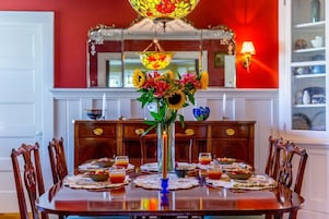 Uma mesa de jantar posta com jogos americanos, velas e um arranjo de flores.