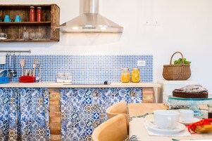 Cozinha com painel de azulejos, prateleiras de madeira e suporte para panelas suspenso.