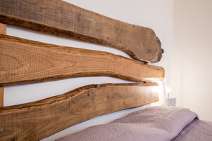 Cama com cabeceira de madeira e manta texturizada.