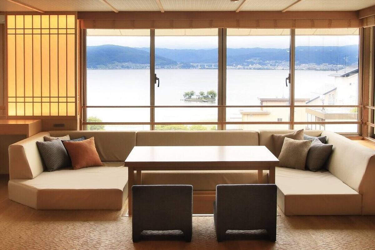 Um quarto com uma janela grande, um sofá, uma mesa e uma cadeira.