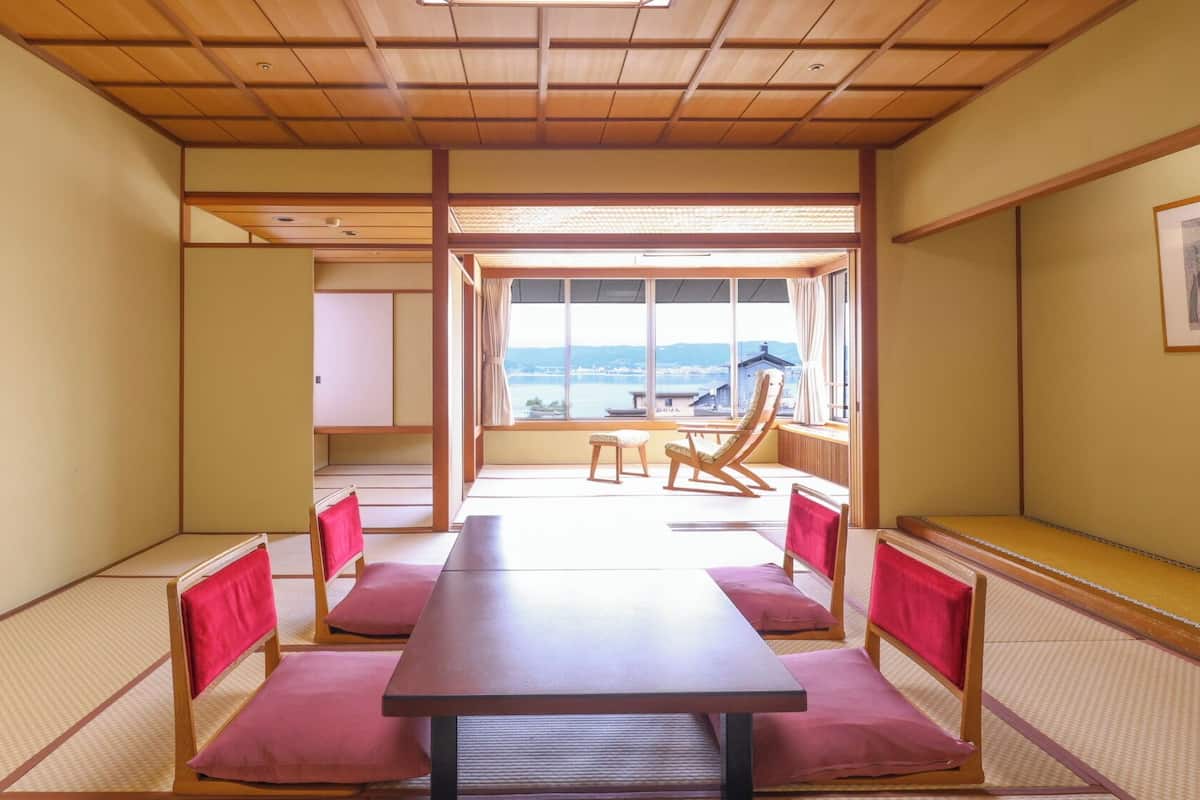 Um quarto japonês tradicional com tatames, uma mesa de madeira baixa e almofadas vermelhas.