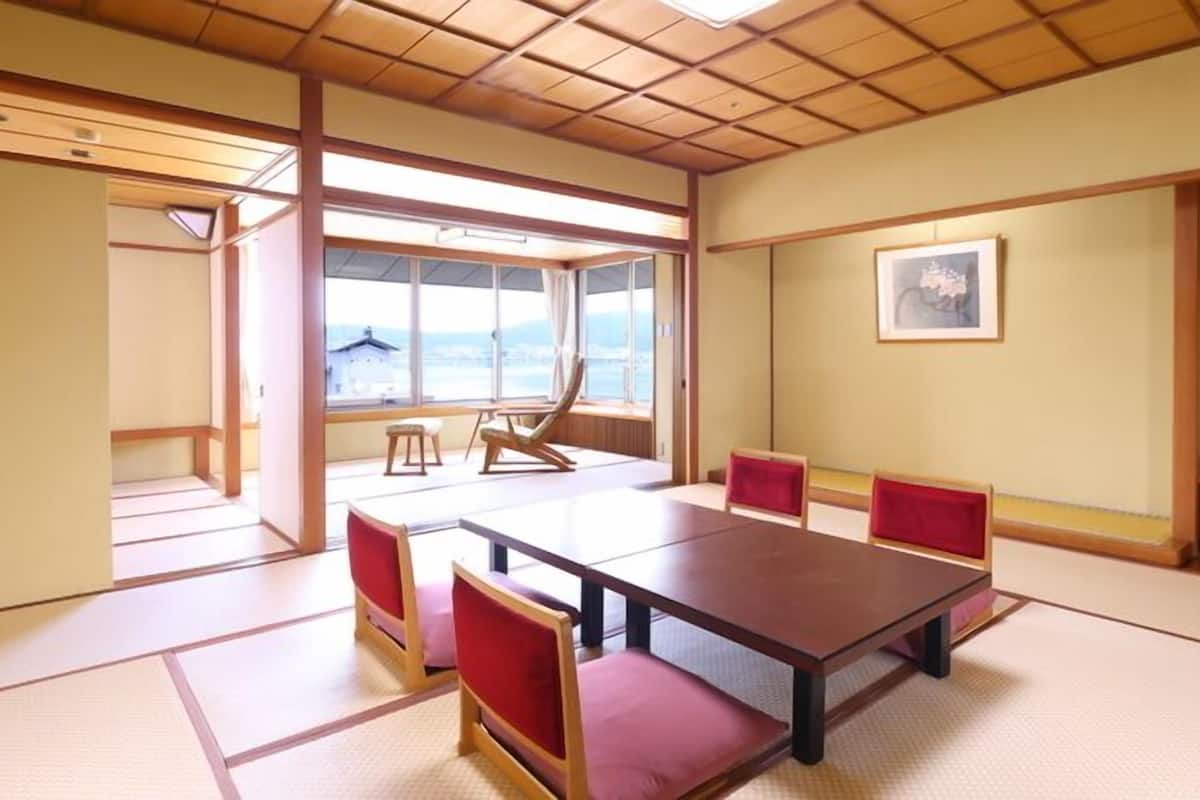 Um quarto japonês tradicional com tatames, uma mesa baixa e almofadas vermelhas.