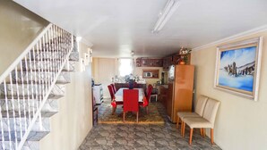 Uma área de refeições com mesa e cadeiras, uma cozinha equipada e uma escada com corrimão.