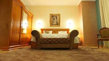 Quarto com cama, guarda-roupa de madeira, um quadro na parede e uma cadeira.