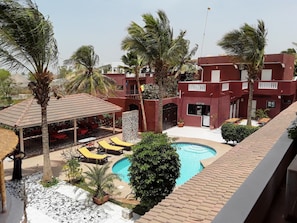 Um hotel com piscina, espreguiçadeiras e área de recepção.