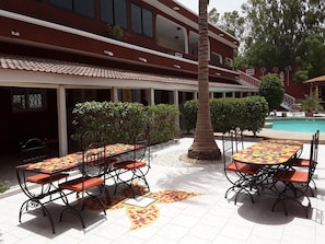 Um pátio com área de estar externa, piscina e um edifício com fachada vermelha.