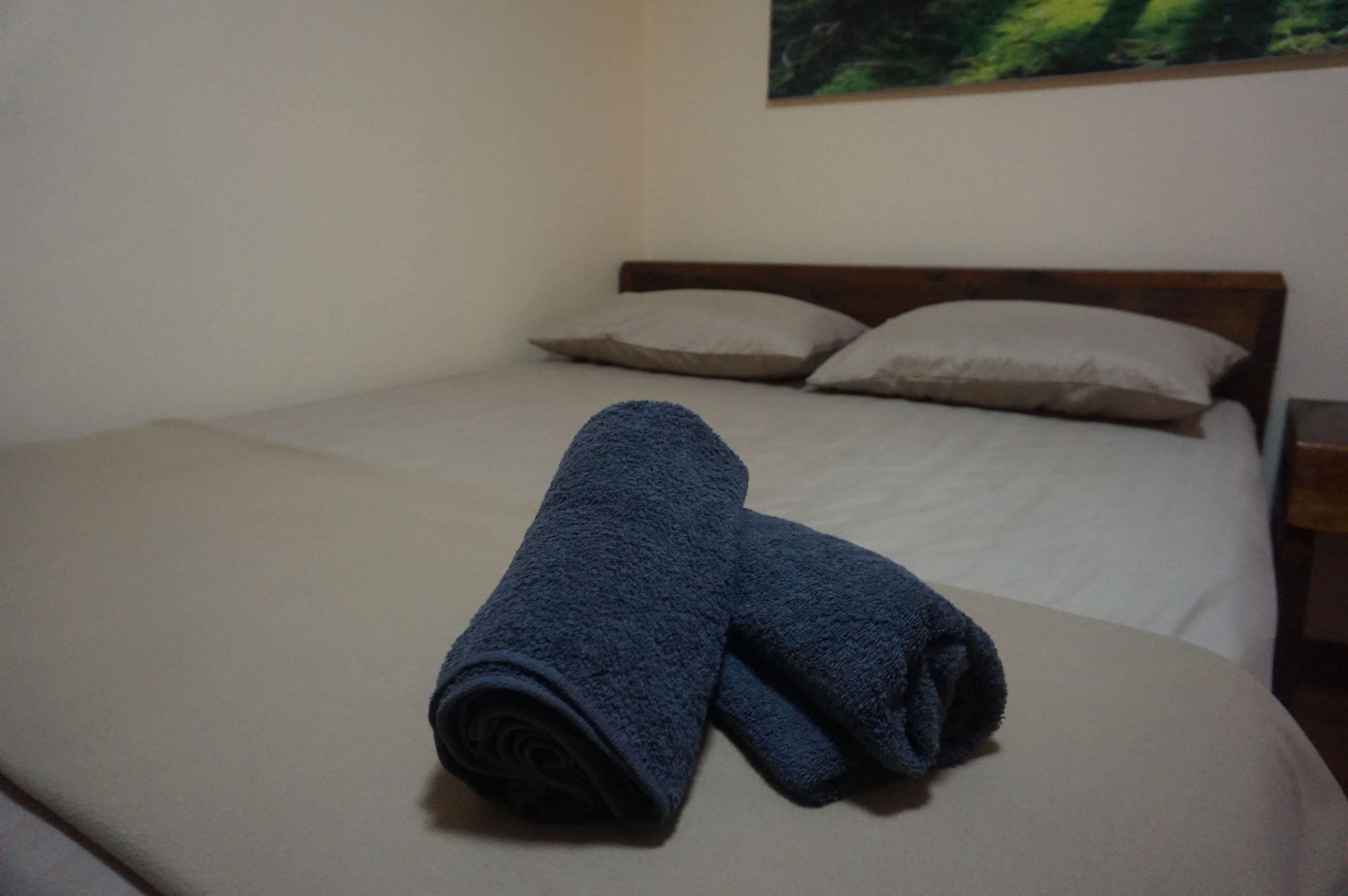 Cama bem arrumada com uma toalha azul enrolada sobre ela.