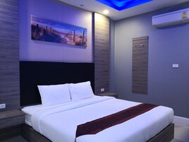 Quarto moderno com uma cama grande, mesa de cabeceira, ar-condicionado fixado na parede e uma pintura de uma cena de praia.