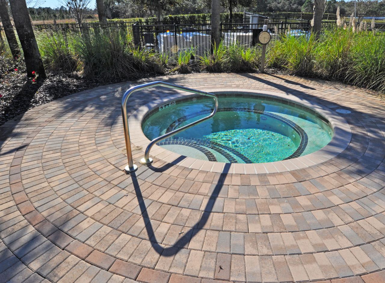 Piscina circular com escada de metal e deck revestido com azulejos.
