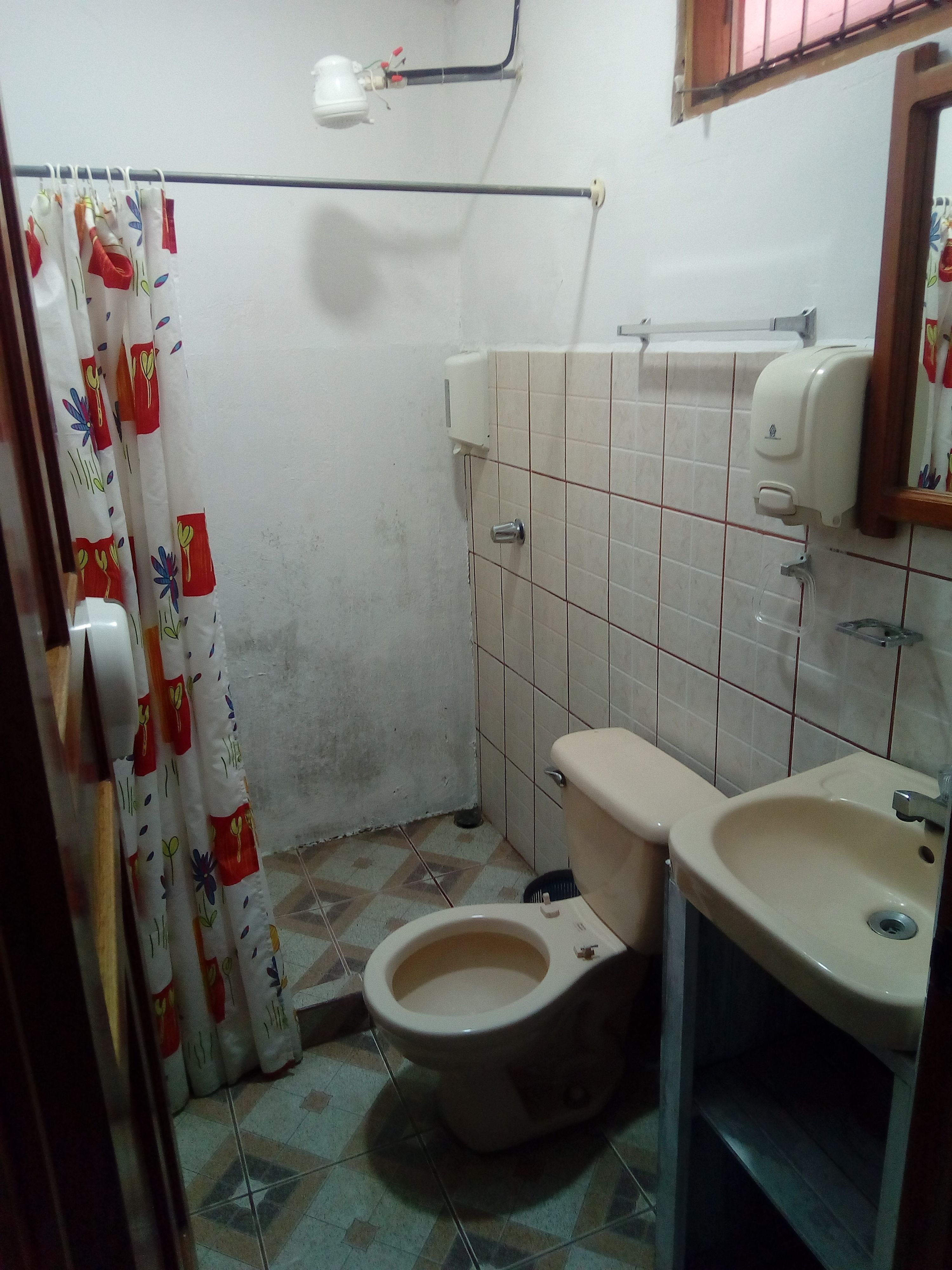 Casa de banho pequena com sanita, lavatório e cortina de chuveiro.