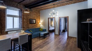 Uma sala de estar moderna com parede de tijolos, piso de madeira, um sofá, uma mesa de centro e uma área de jantar com cadeiras.
