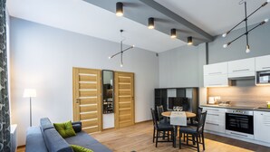 Uma sala de estar moderna com sofá, mesa de jantar com cadeiras e área de cozinha com armários e eletrodomésticos.
