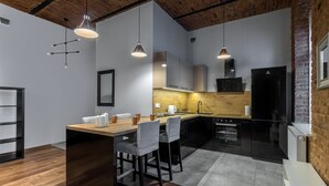 Cozinha moderna com ilha de madeira, eletrodomésticos pretos e iluminação pendente.