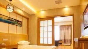 Quarto de hotel com duas camas, piso de madeira, uma janela grande e uma televisão sobre um suporte de madeira.