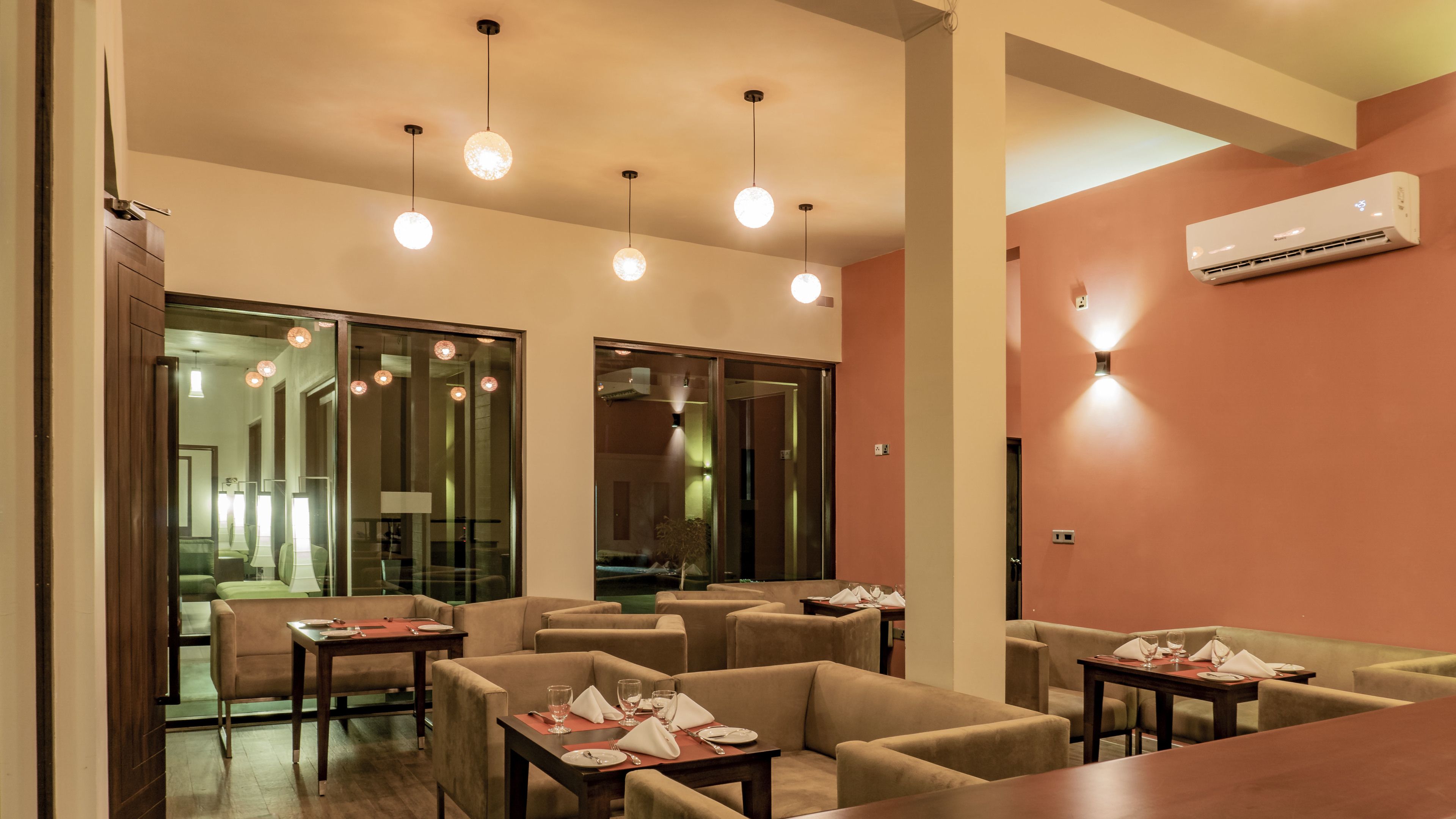 Um restaurante com várias mesas, cadeiras e luminárias pendentes.
