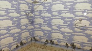 Quarto com paredes em padrão de nuvens e uma cena de praia na parte inferior.