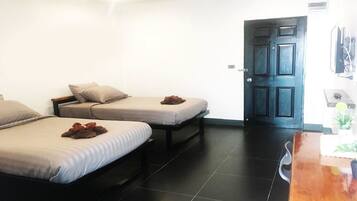 Quarto de hotel com duas camas, uma escrivaninha de madeira e uma porta escura.