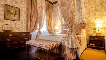 Quarto de hotel com cama, mesas de cabeceira, luminária, cesto ao lado da cama e um quadro na parede.