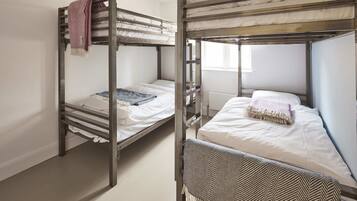 Quarto com beliche, janela, radiador e um cobertor em uma das camas.