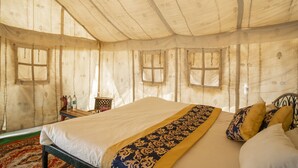 Um quarto em tenda tradicional com uma cama, cortinas estampadas e uma janela.