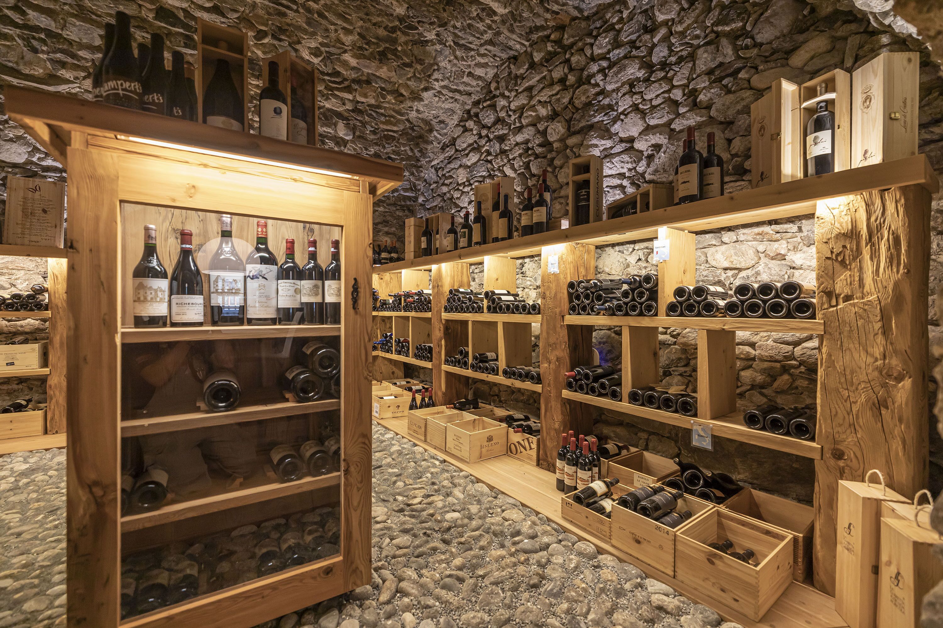 Uma adega com estantes e prateleiras de madeira repletas de garrafas.