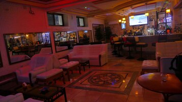 Uma área de bar com assentos e uma tela de televisão.