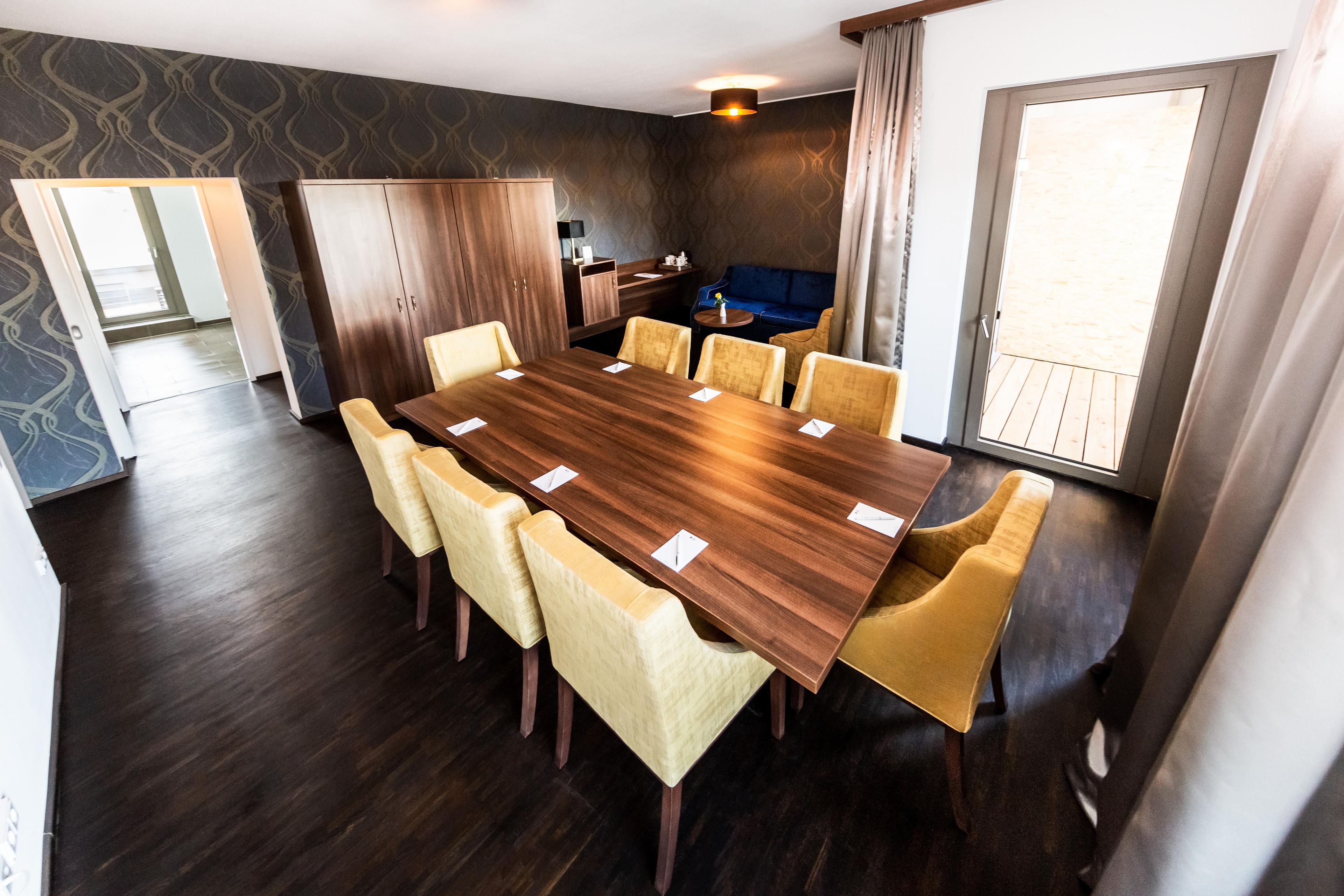Uma sala de conferências com uma grande mesa de madeira, cadeiras amarelas e um sofá azul.