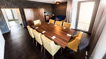 Uma sala de conferências com uma grande mesa de madeira, cadeiras amarelas e um sofá azul.