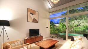 Uma sala de estar moderna com um sofá, mesa de centro e uma televisão sobre um armário de madeira.