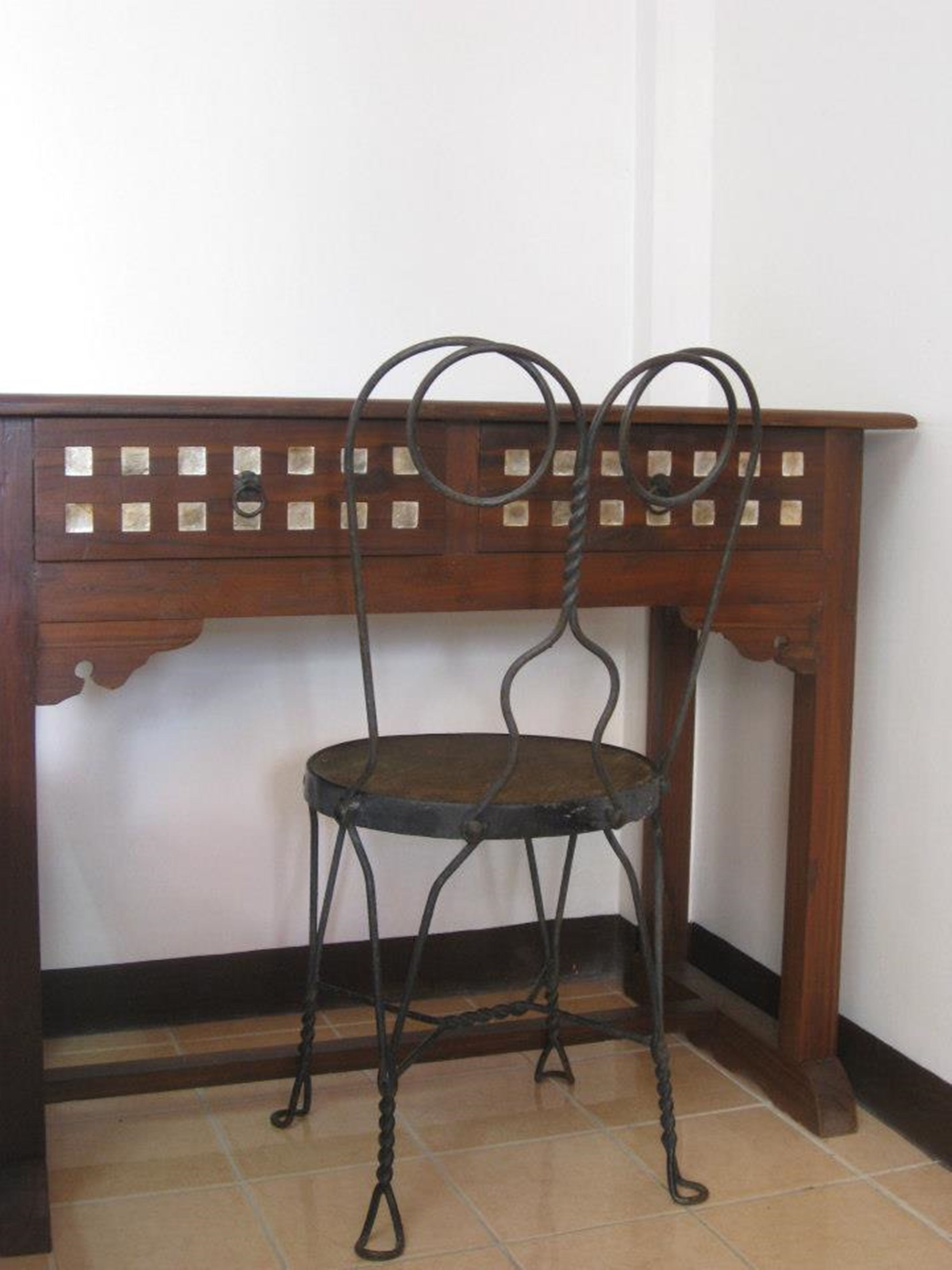 Uma cadeira de metal com encosto curvo e uma mesa de madeira com design em grade.