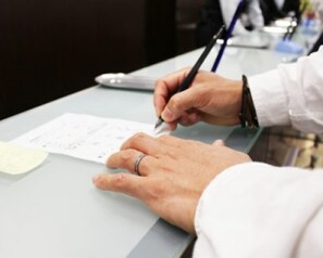 Uma pessoa assinando um documento sobre uma mesa com uma caneta.