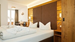 Quarto de hotel com uma cama grande, cabeceira de madeira, uma escrivaninha e uma cadeira.