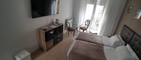 Quarto com uma cama, televisão, escrivaninha e uma cadeira.
