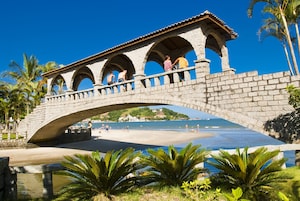 Uma ponte de pedra com arcos sobre uma praia.