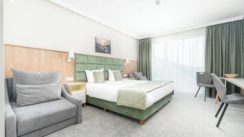 Quarto de hotel com cama, sofá, escrivaninha e cadeira.