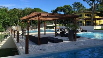 Uma área de piscina com pergolado, espreguiçadeiras e uma piscina pequena.