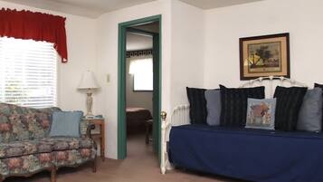 Um quarto com um sofá floral, um sofá azul com almofadas, uma luminária e um quadro na parede.