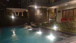 Piscina com design moderno, rodeada por um muro de pedra e um pequeno jardim.