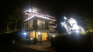 Um edifício com vários andares e uma varanda, iluminado por luzes externas.