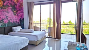 Quarto de hotel com duas camas, uma janela grande com cortinas, vista para área verde e varanda com uma cadeira.