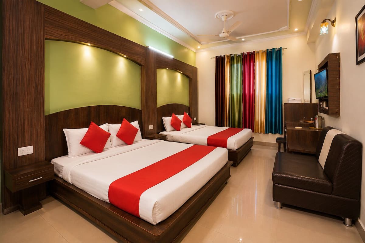 Quarto de hotel com duas camas, um sofá, uma televisão e banheiro com cortina de chuveiro.