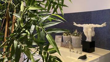 Casa de banho com lavatório, estátua branca e parede revestida de azulejos azuis.