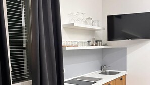 Cozinha moderna com fogão embutido, pia e televisão de tela plana fixada acima do balcão.