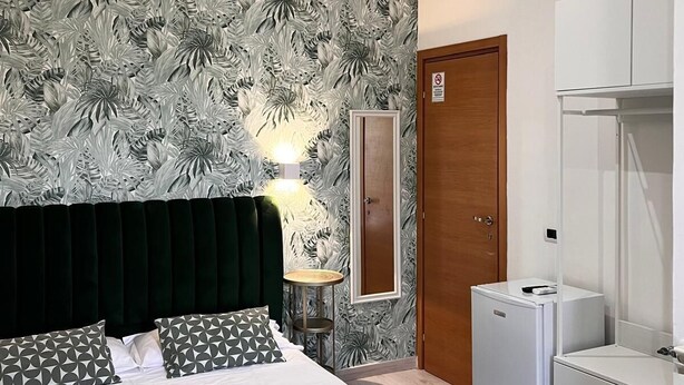 Quarto com cama, mesa de cabeceira, espelho, guarda-roupa e ar condicionado.