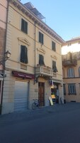 Um edifício com uma persiana fechada, uma bicicleta estacionada em frente e uma placa para pizzaria e pastelaria.