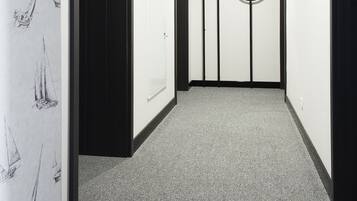 Um corredor com chão coberto de carpete, paredes em preto e branco e uma porta com espelho.