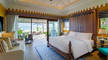 Um quarto espaçoso com uma cama grande, um sofá e um espaço de jantar com vista para a praia.